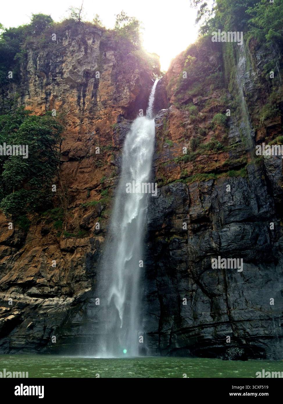 A fairly high waterfall whose water comes out of a gap in a rock cliff ...