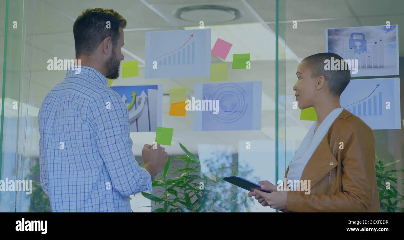 Office professionals analyzing charts on glass partition in office ...