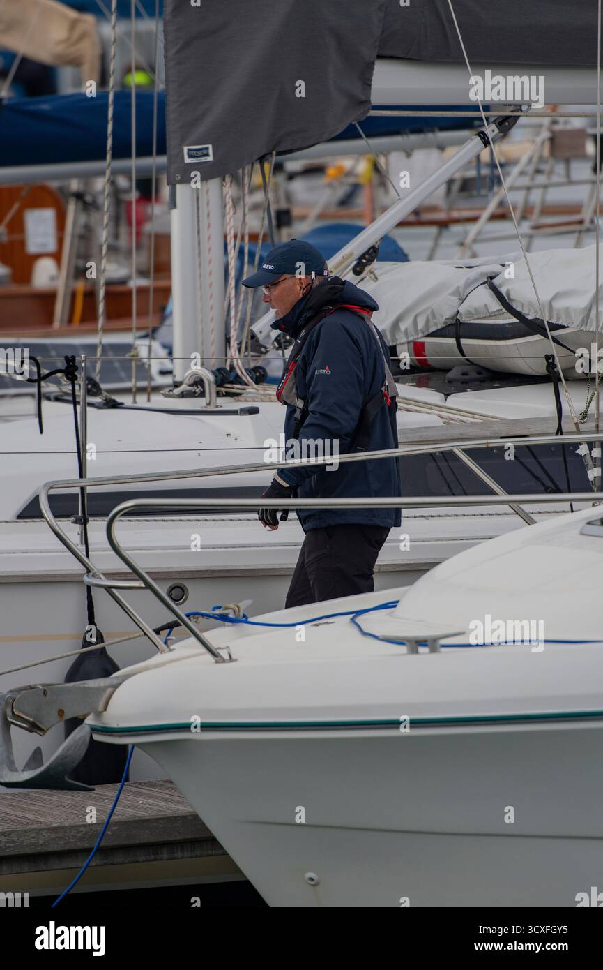 yachtsman walking on a pontoon or jetty in a busy Solent marina on the ...