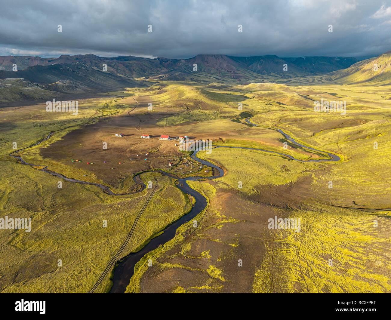 Remote settlement in scenic valley with vibrant fields, river curves ...