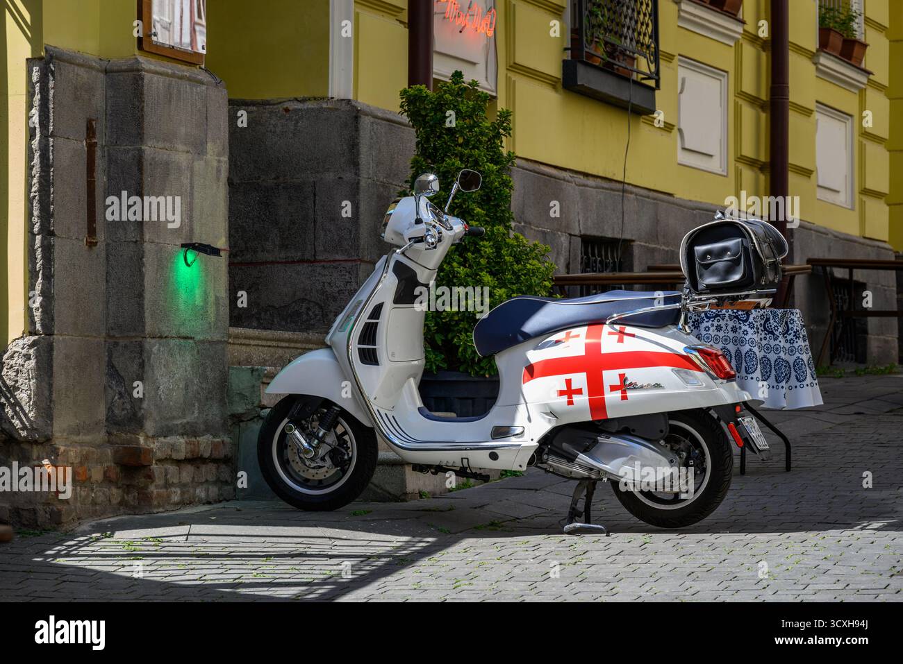 White scooter with Georgian flag parked on cobblestone street in ...