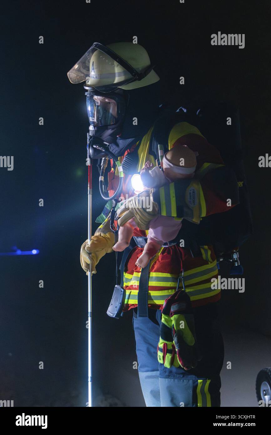 Firefighter with breathing mask and child dummy during a night-time ...