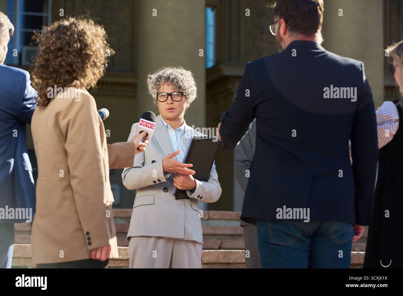 Middle aged Caucasian woman with curly gray hair standing on steps ...