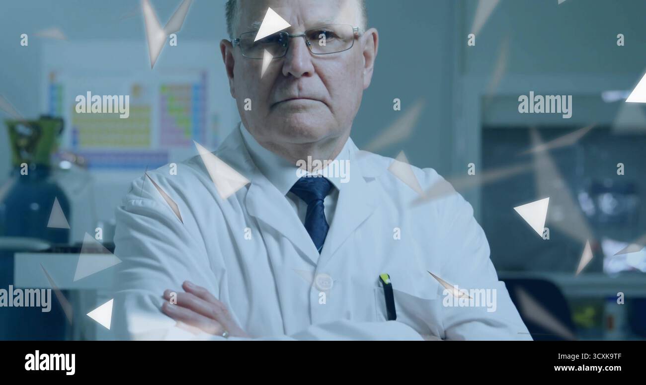 Senior scientist wearing lab coat crossing arms in lab with periodic ...