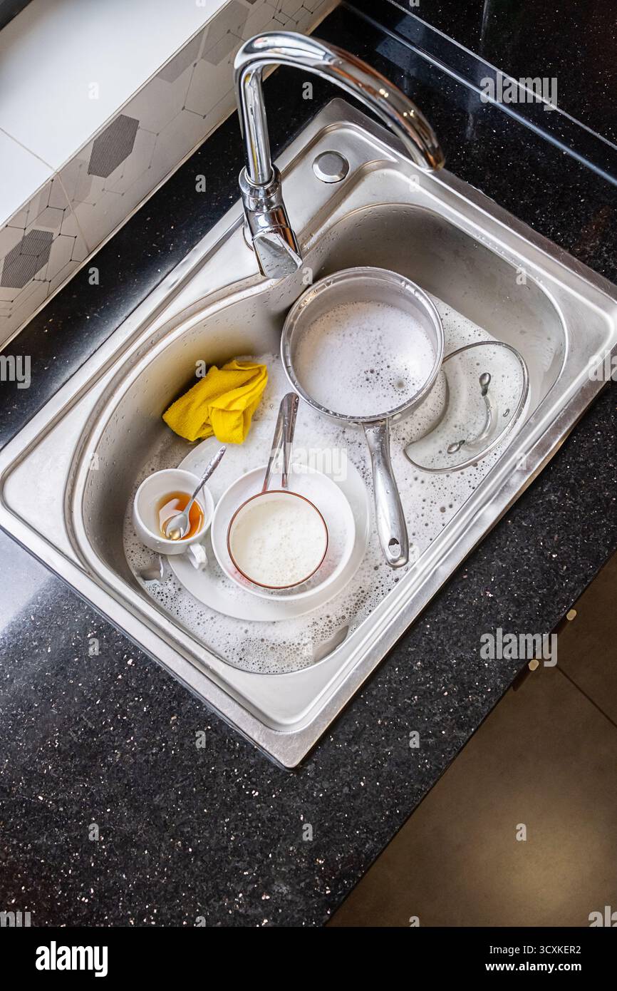 Dirty dishes with soapy water in kitchen sink. Household chore concept ...