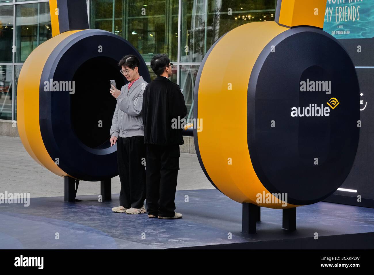 Visitors stand near giant head phones on the first media day of the ...