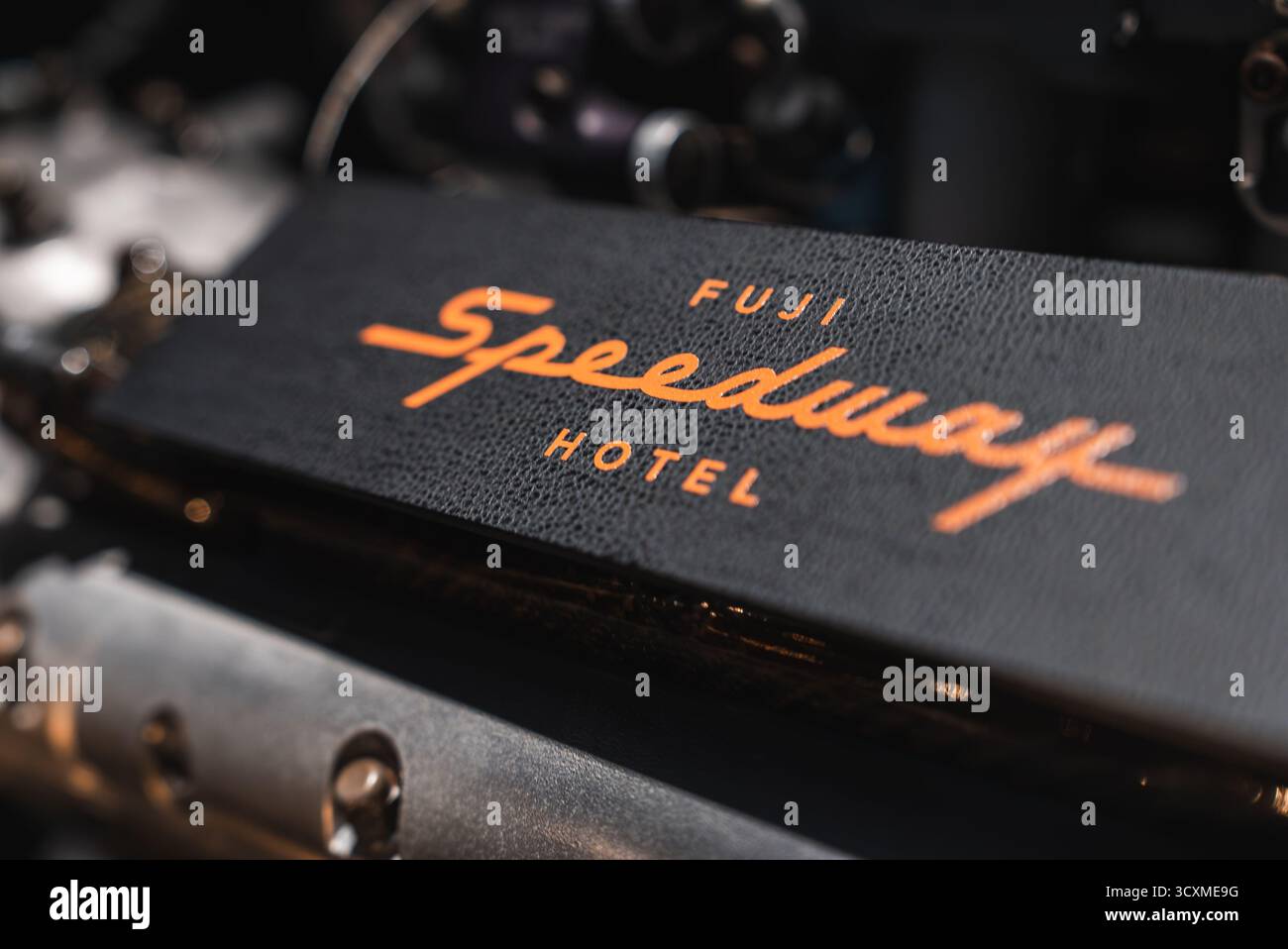 Black plaque with Fuji Speedway Hotel text beside blurred engine parts ...