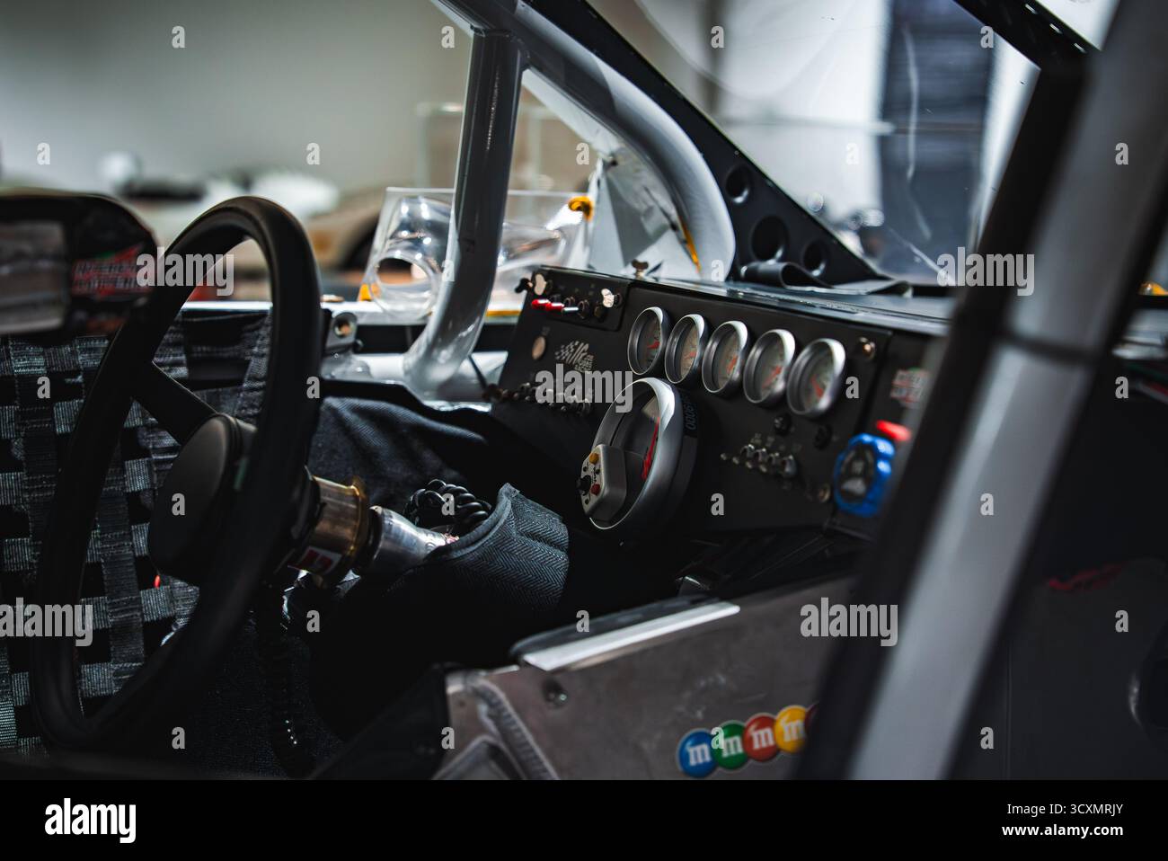 Race car cockpit close up with gauges, switches, wheel, and roll cage ...