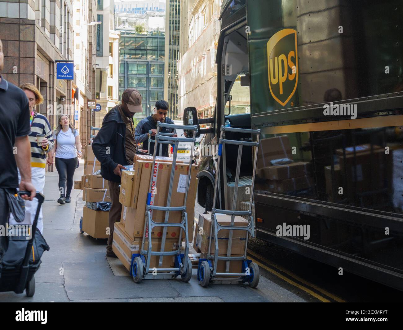 UPS parcel delivery van with workers loading trolleys, City of London ...