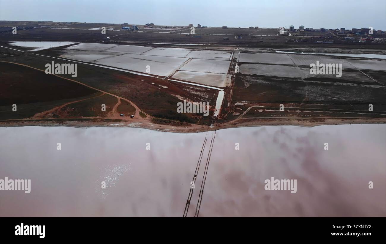 Aerial view flying over pink salt lake and evaporation ponds. Media ...