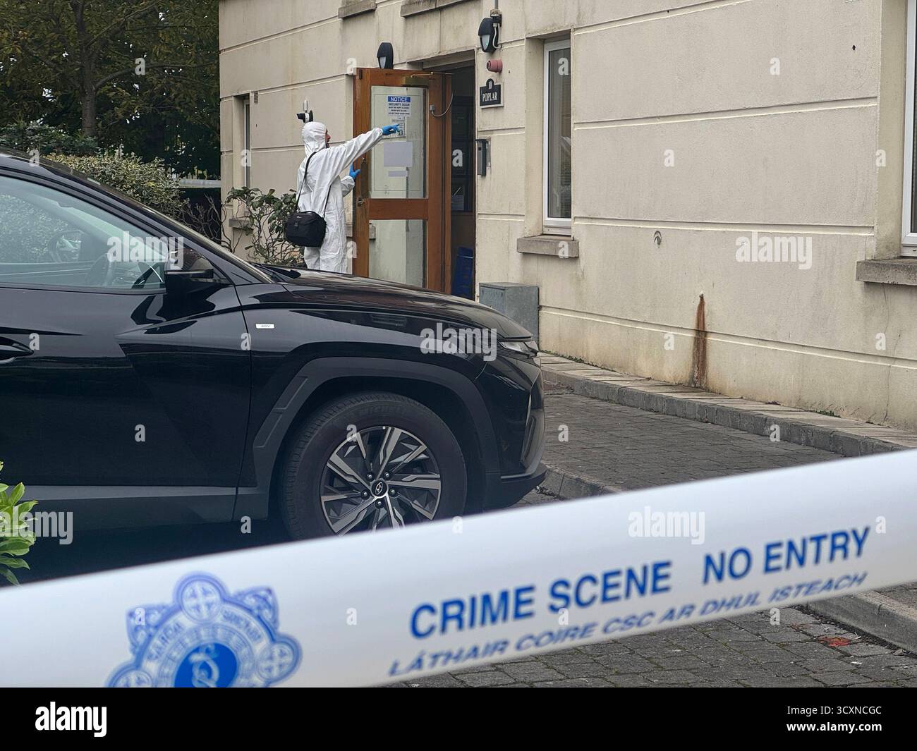 Members of the Garda Technical Bureau behind a crime scene cordon ...