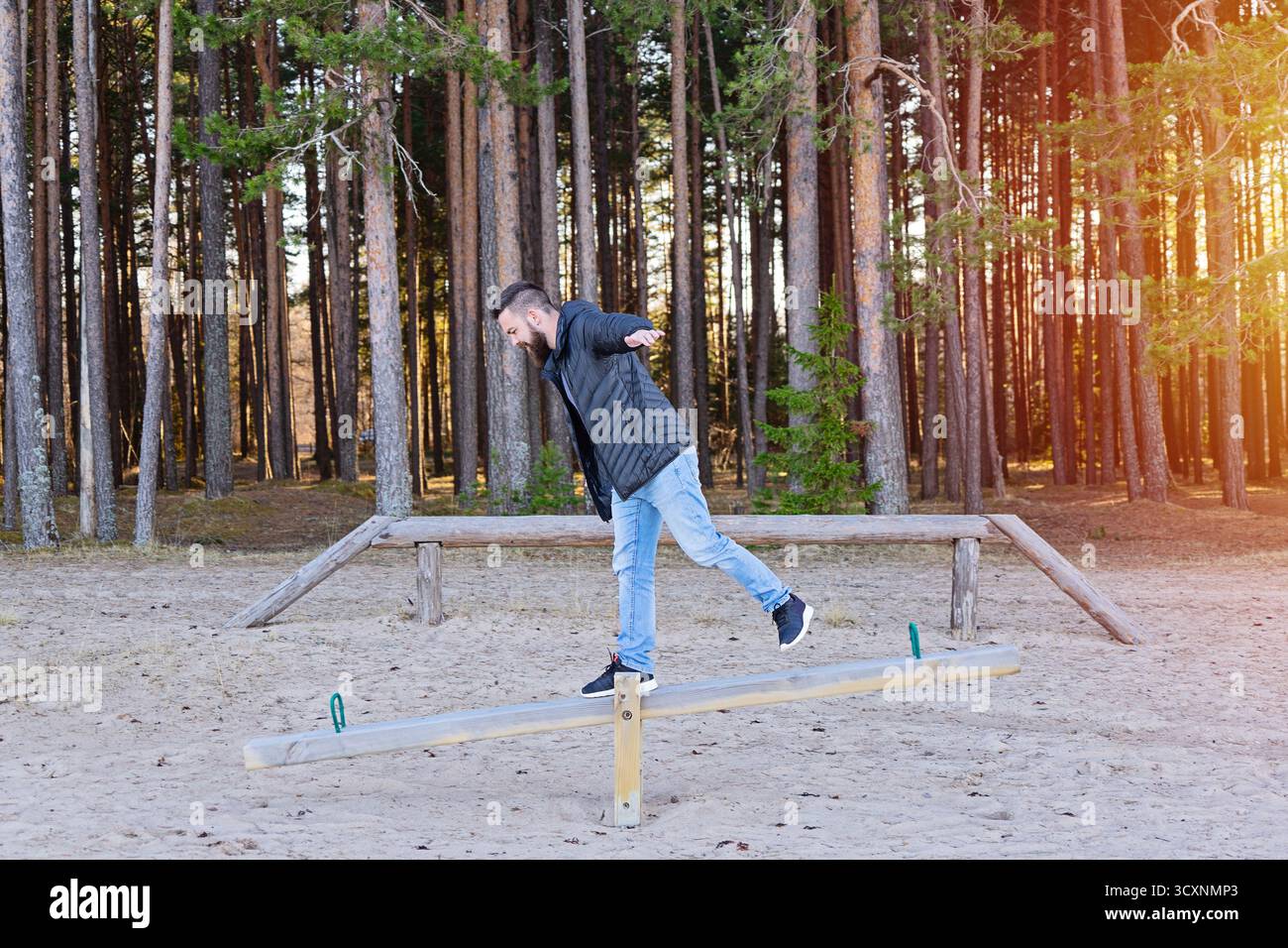 Young person practices balance on narrow beam in sandy forest ...