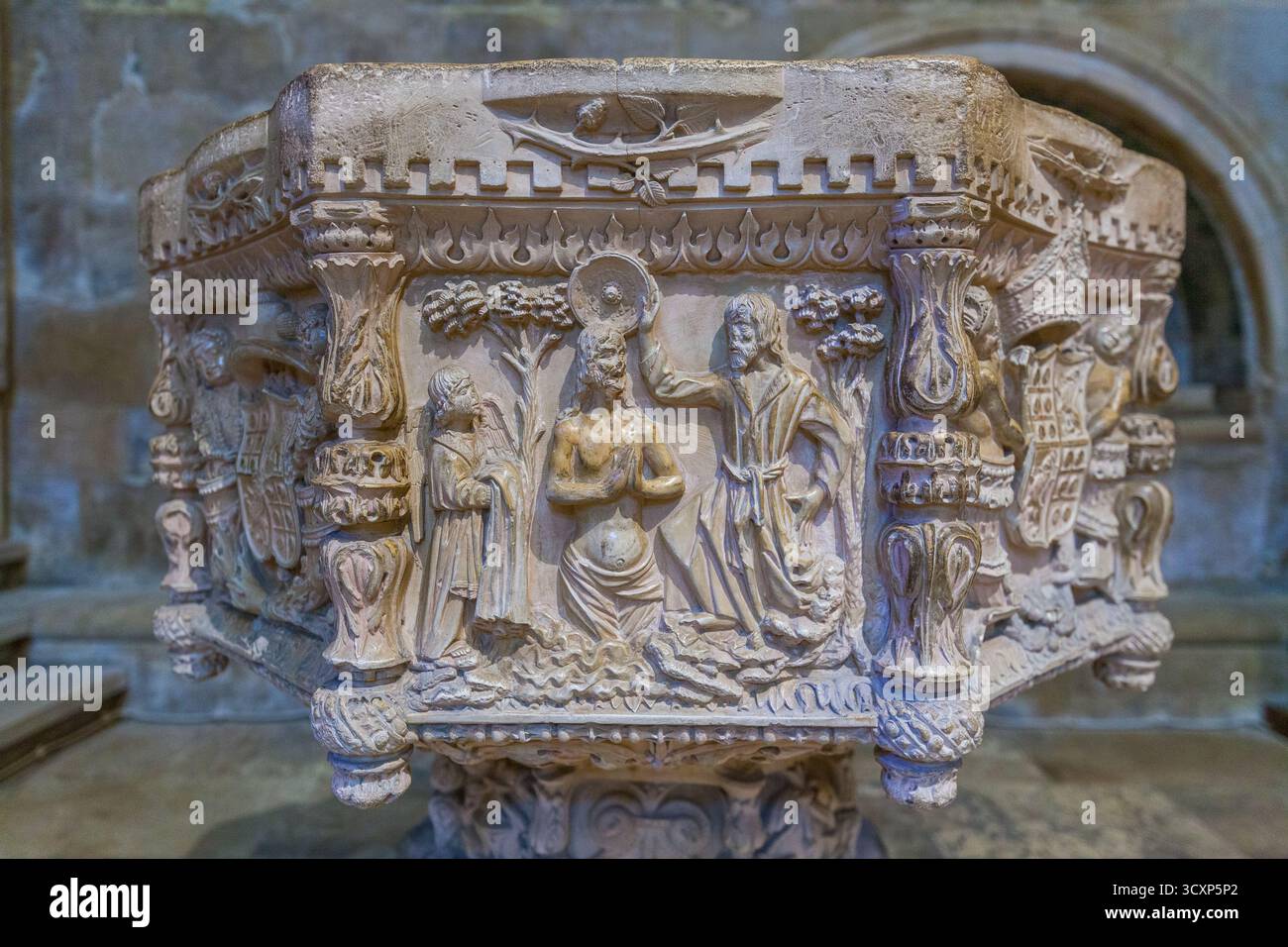 An intricately carved stone baptismal font depicts a religious scene ...