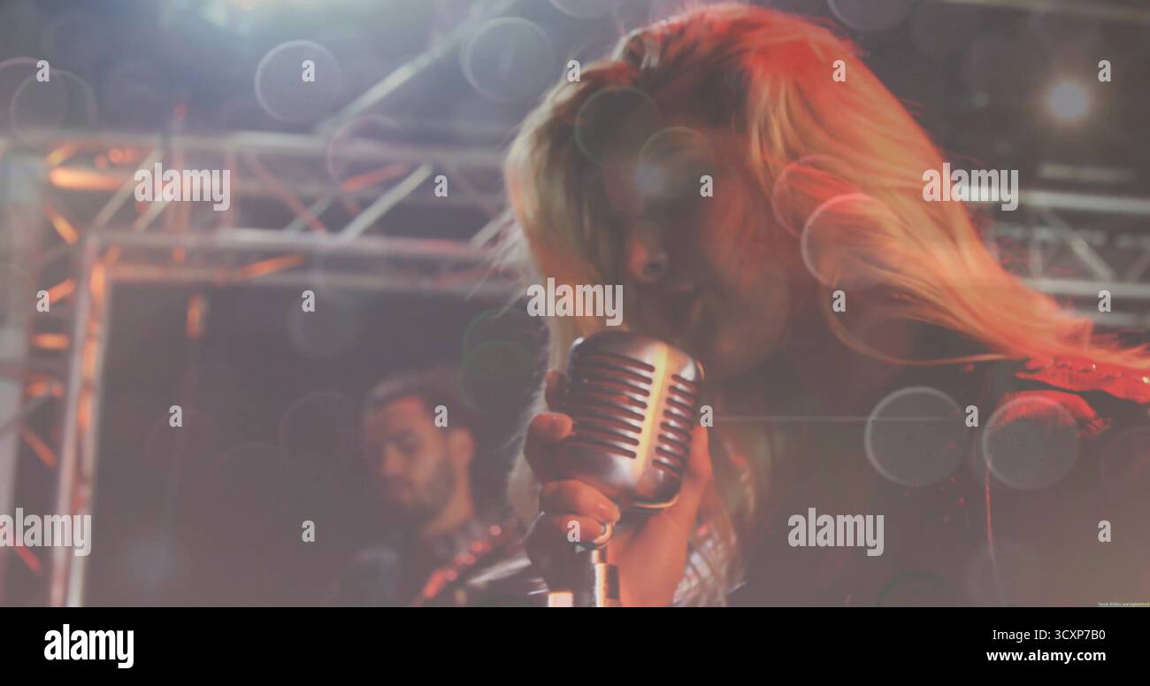 Singing female wearing stage attire holding retro microphone on stage ...