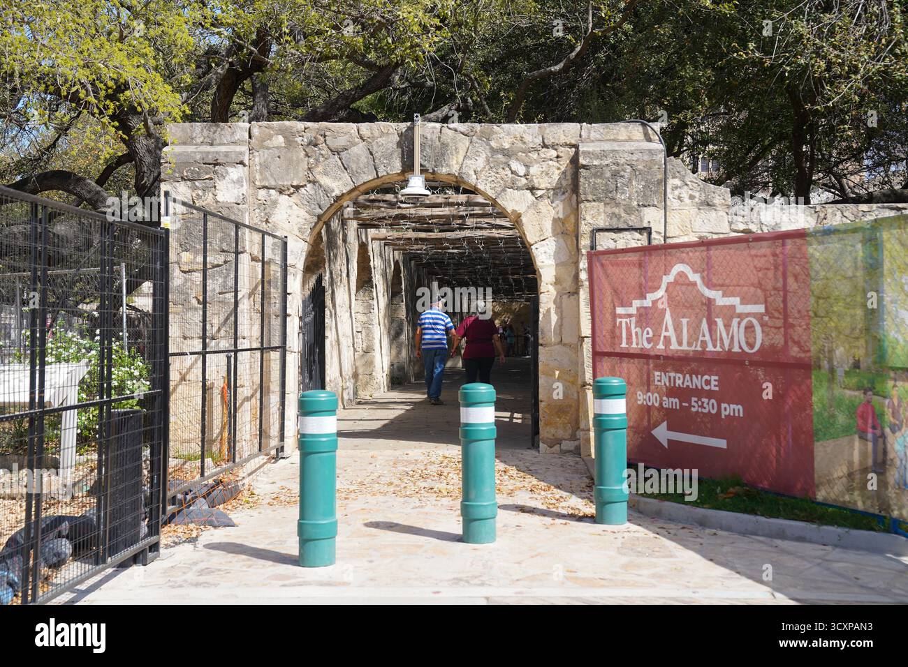 Visitors walk through the stone archway entrance of the Alamo Mission ...
