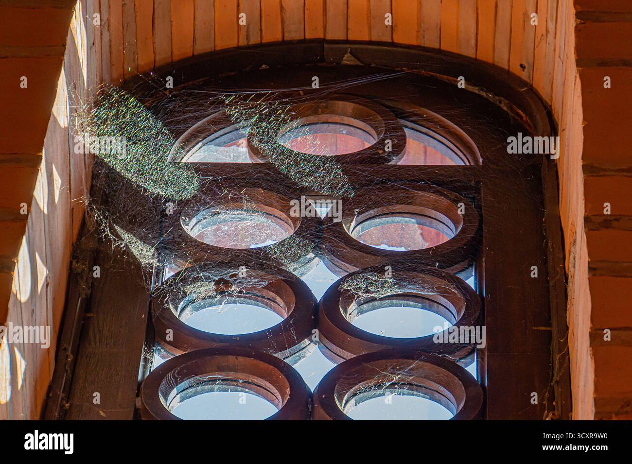 An old, cobweb-covered window in a neglected building is shown ...