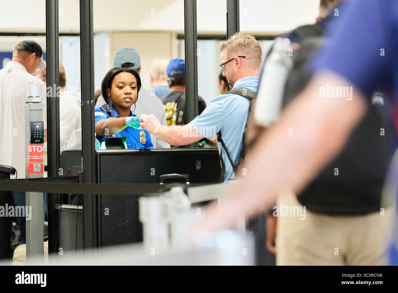 A TSA agent interacts with travelers at a security checkpoint at Dallas ...