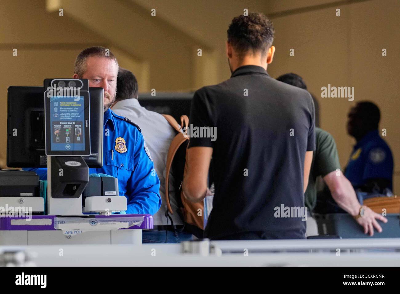 A TSA agent interacts with travelers at a security checkpoint at Dallas ...