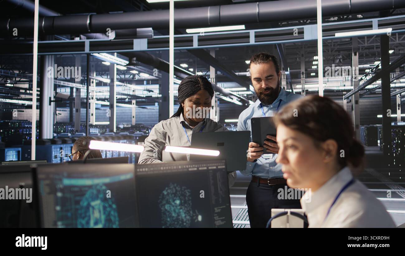 Data scientists working together in server room, reviewing neural ...