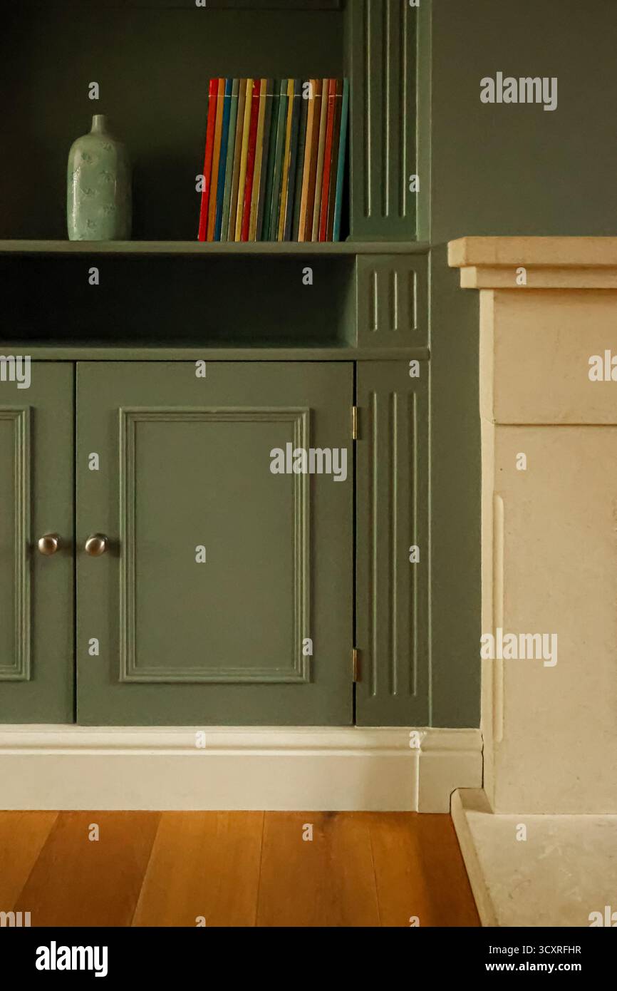 Green built in bookshelf cabinet with colorful books and decorative ...