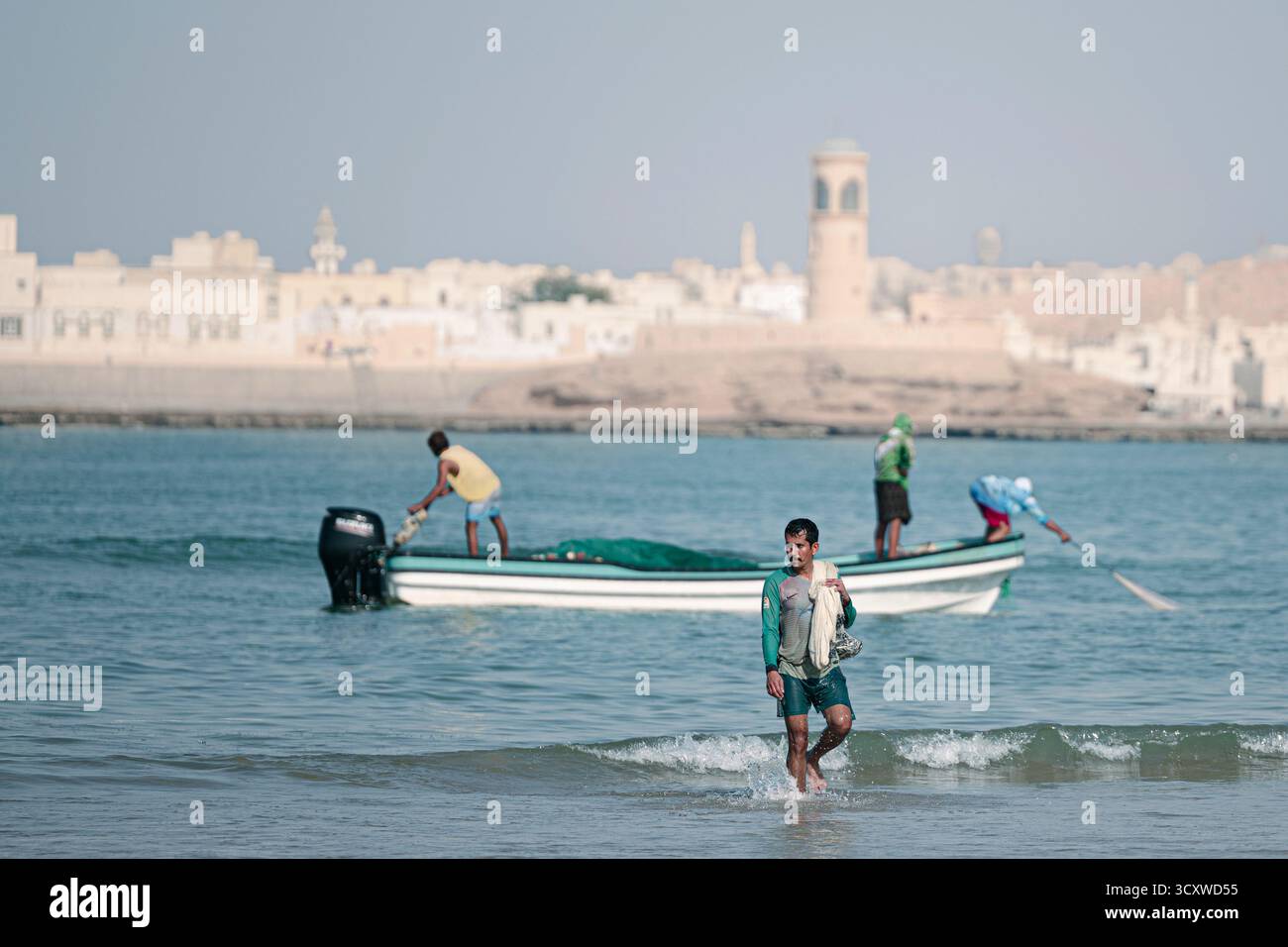 Fisherman steps ashore with his catch, with fishermen in the background ...