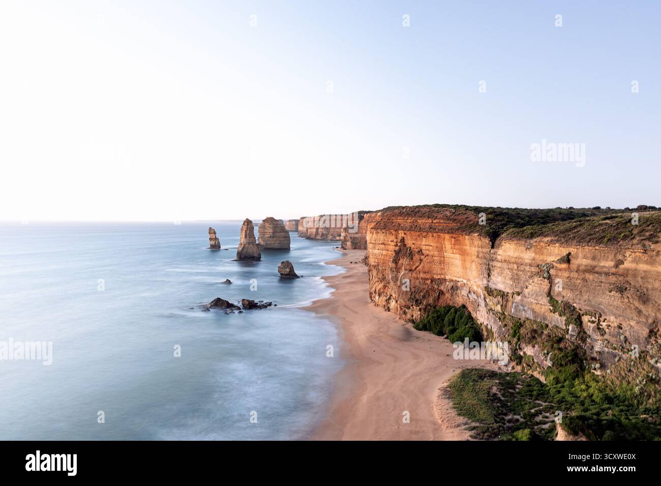 Golden light bathes the towering limestone cliffs and sea stacks of the ...