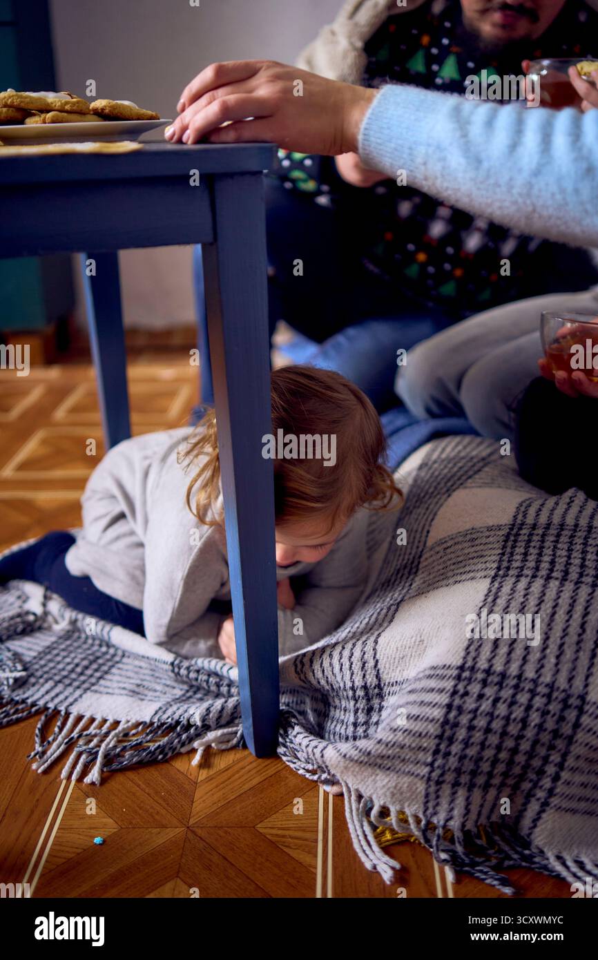 family with daughters toddler and teenager cozy together drinking tea ...