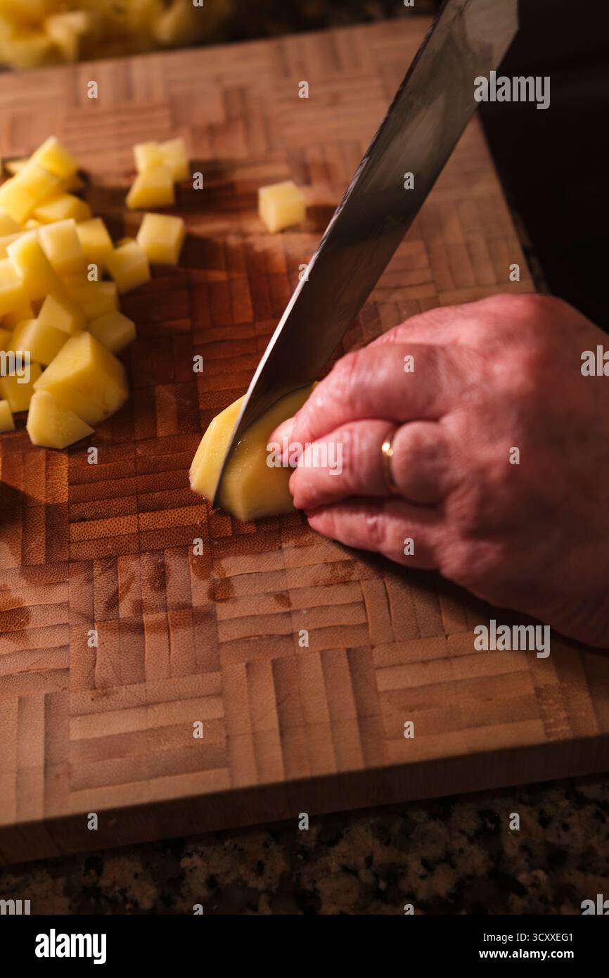 Woman chopping fresh peeled potatoes over wood cutting board. Delicious ...