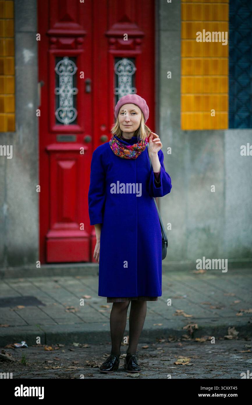 A woman in a lilac coat and beret stands across from a traditional ...