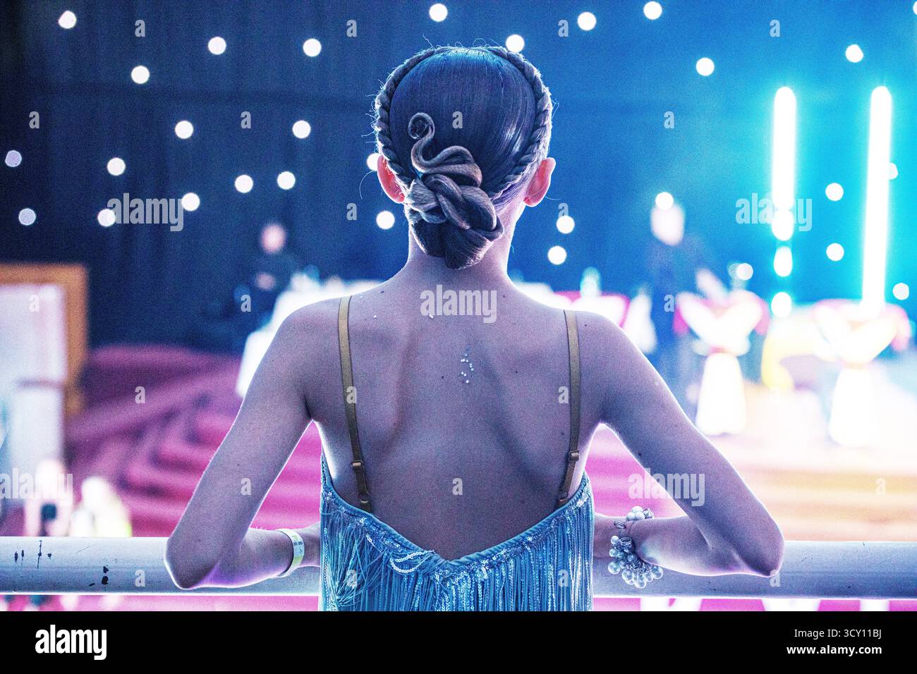 young dancer in a Latin American dress watches a dance tournament from ...