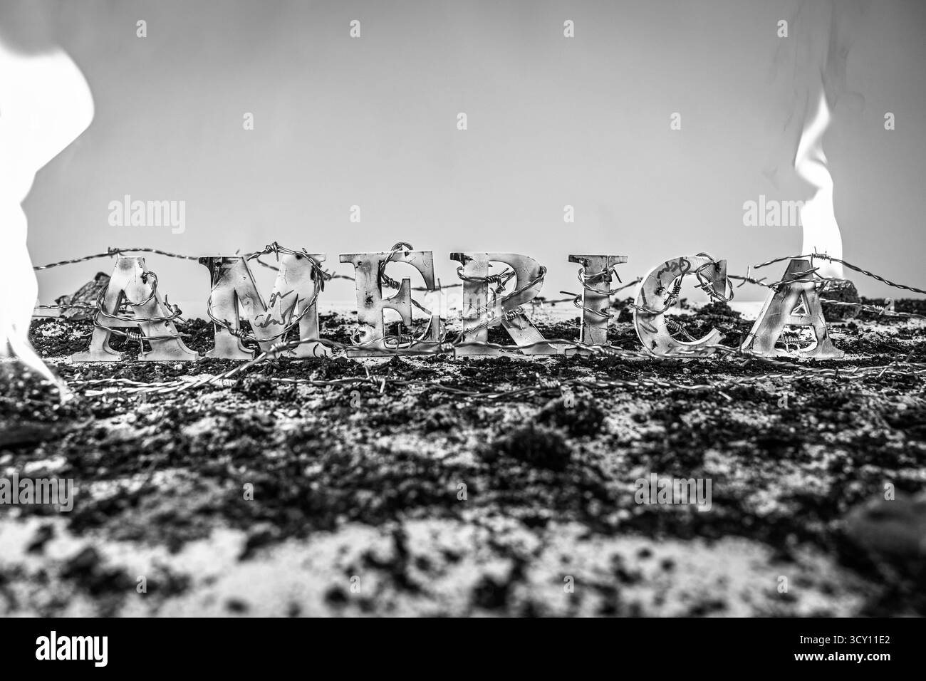 Black and white shot shows barbed wire wrapped around charred and ...