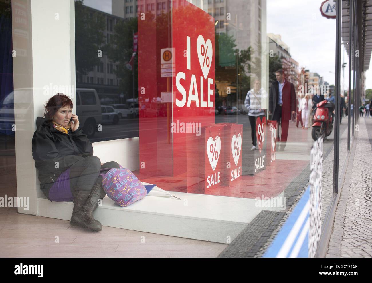 DEU Germany Germany Berlin Woman talking on the phone in a shop window ...