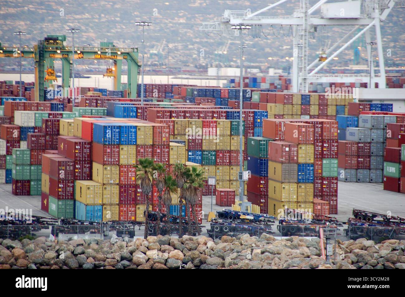 Colorful shipping containers stacked high in a busy industrial port ...