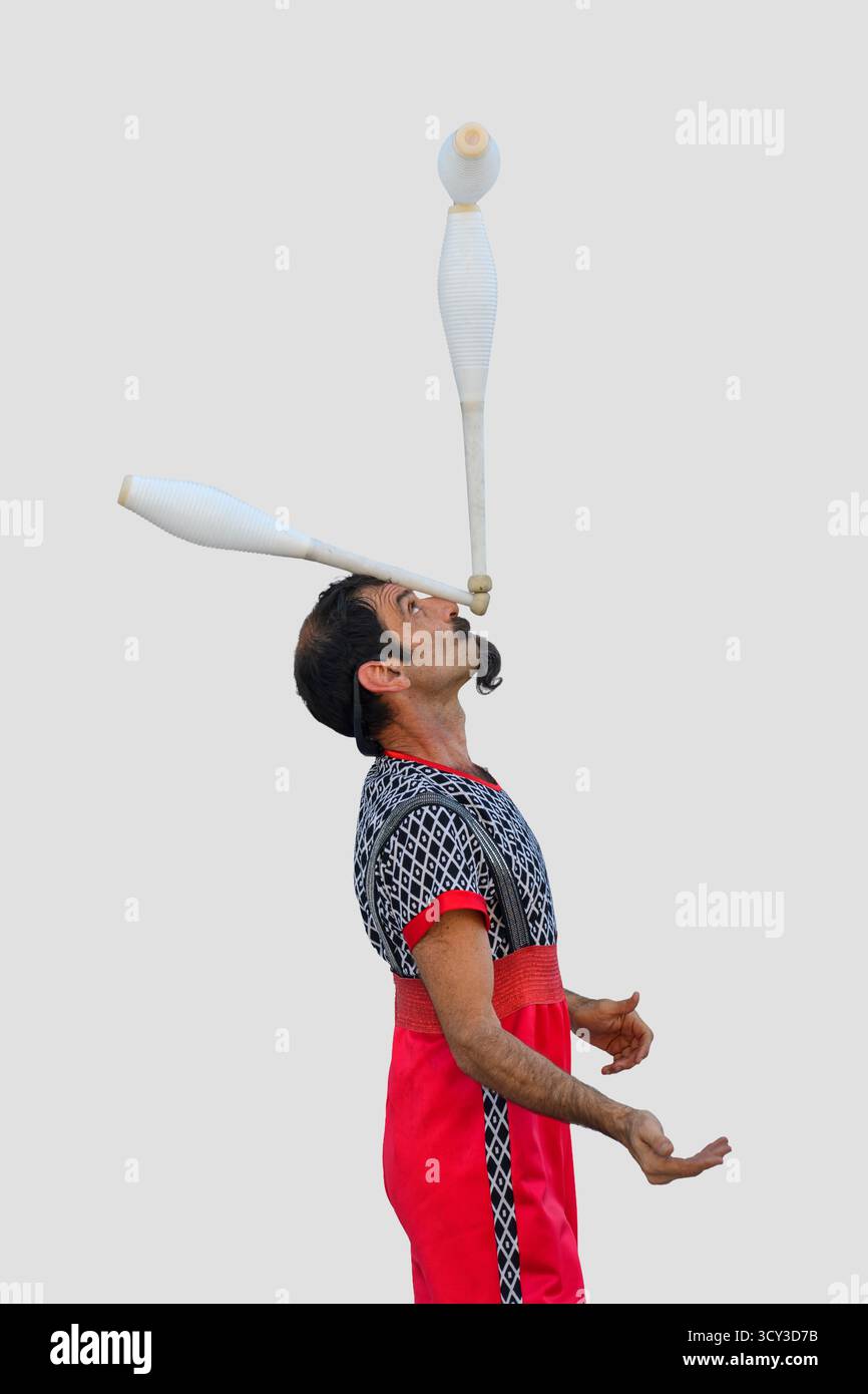 silhouette of a male juggler is balancing three clubs on his face - cut ...