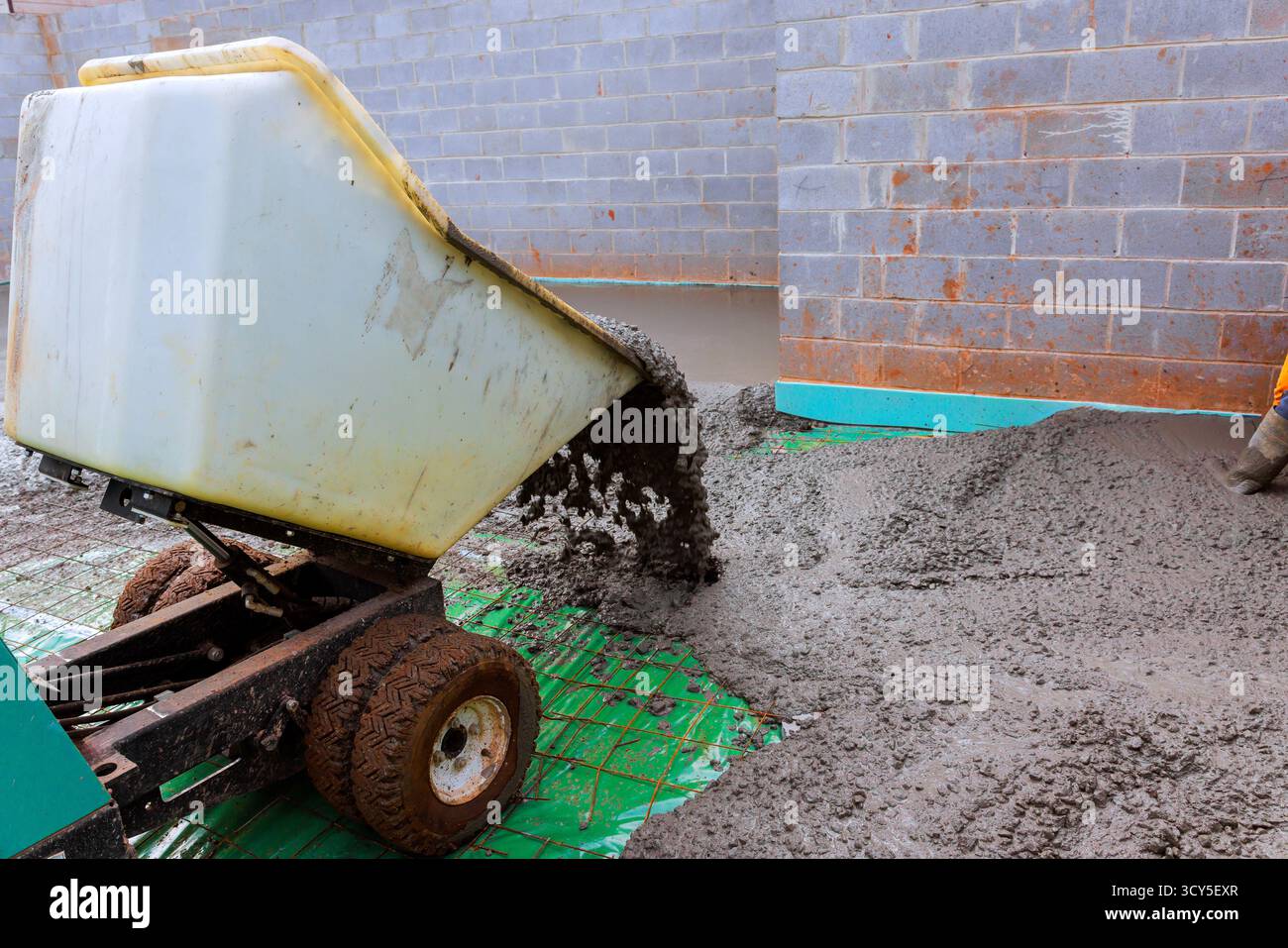 Construction workers are pouring fresh concrete in foundation area ...