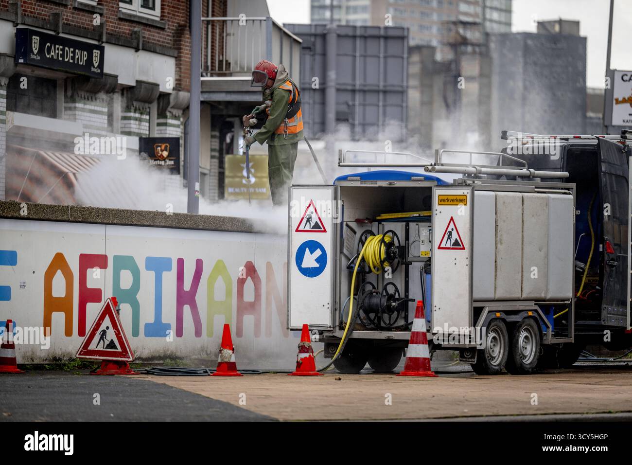 ROTTERDAM - Municipal employee is spraying with a high-pressure cleaner ...
