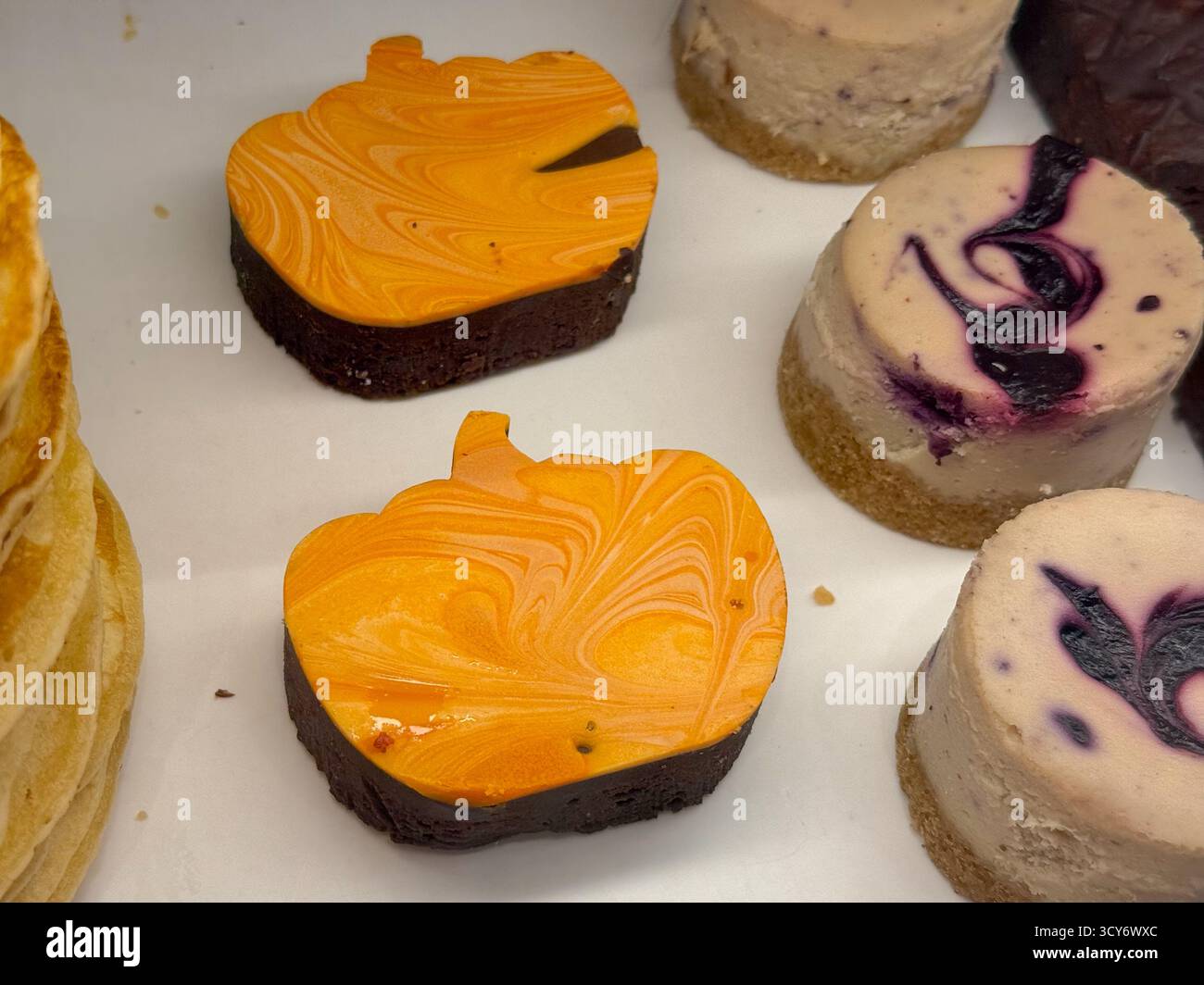 Pumpkin-shaped brownies and mini cheesecakes in bakery display ...