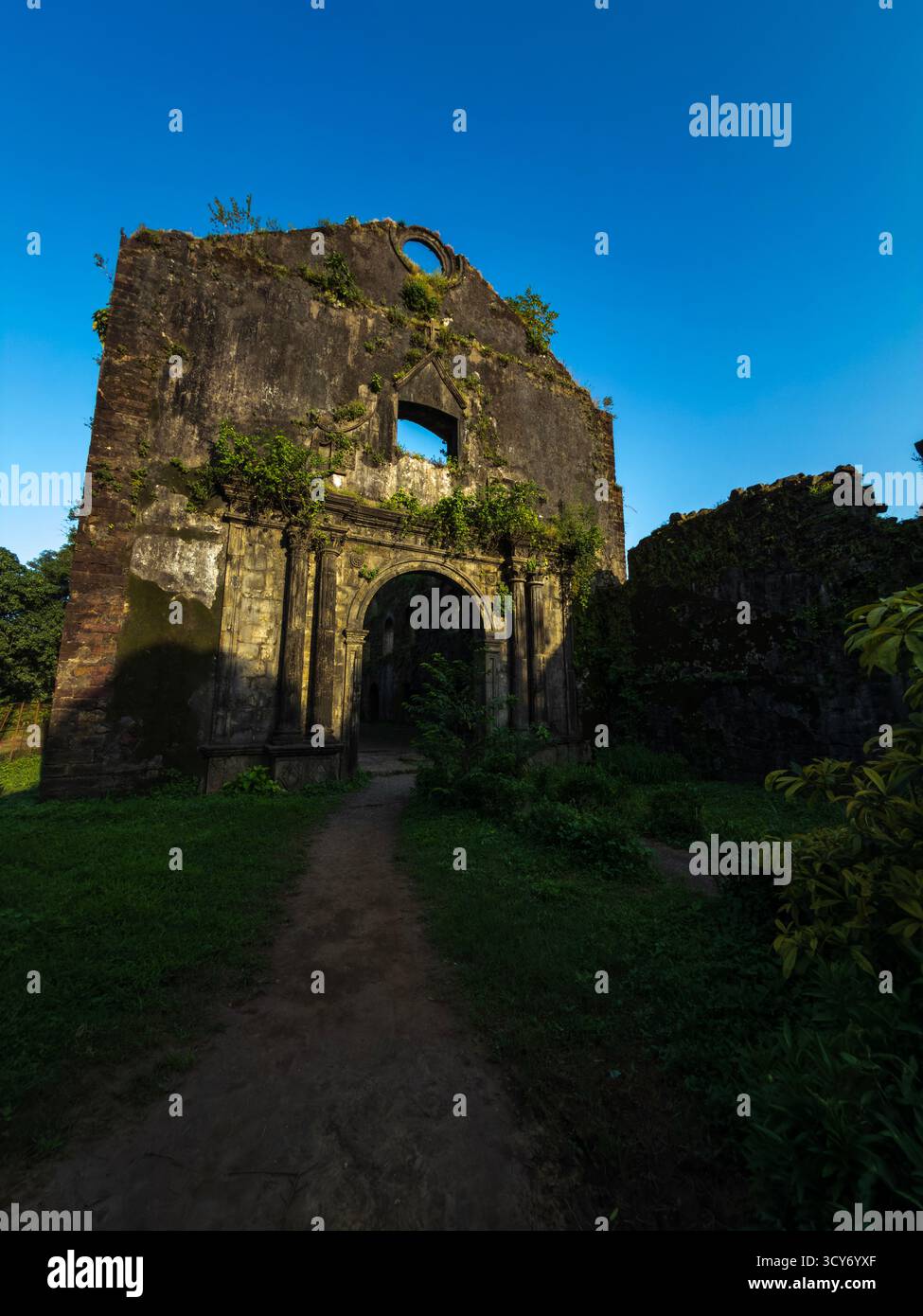 Ancient stone walls and stairways of Vasai Fort surrounded by lush palm ...