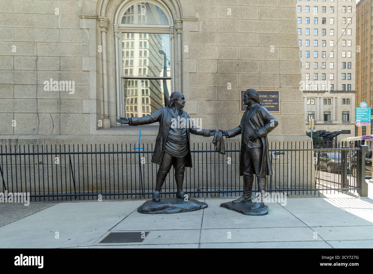 Two statues of men shaking hands. One is wearing a white shirt and the ...
