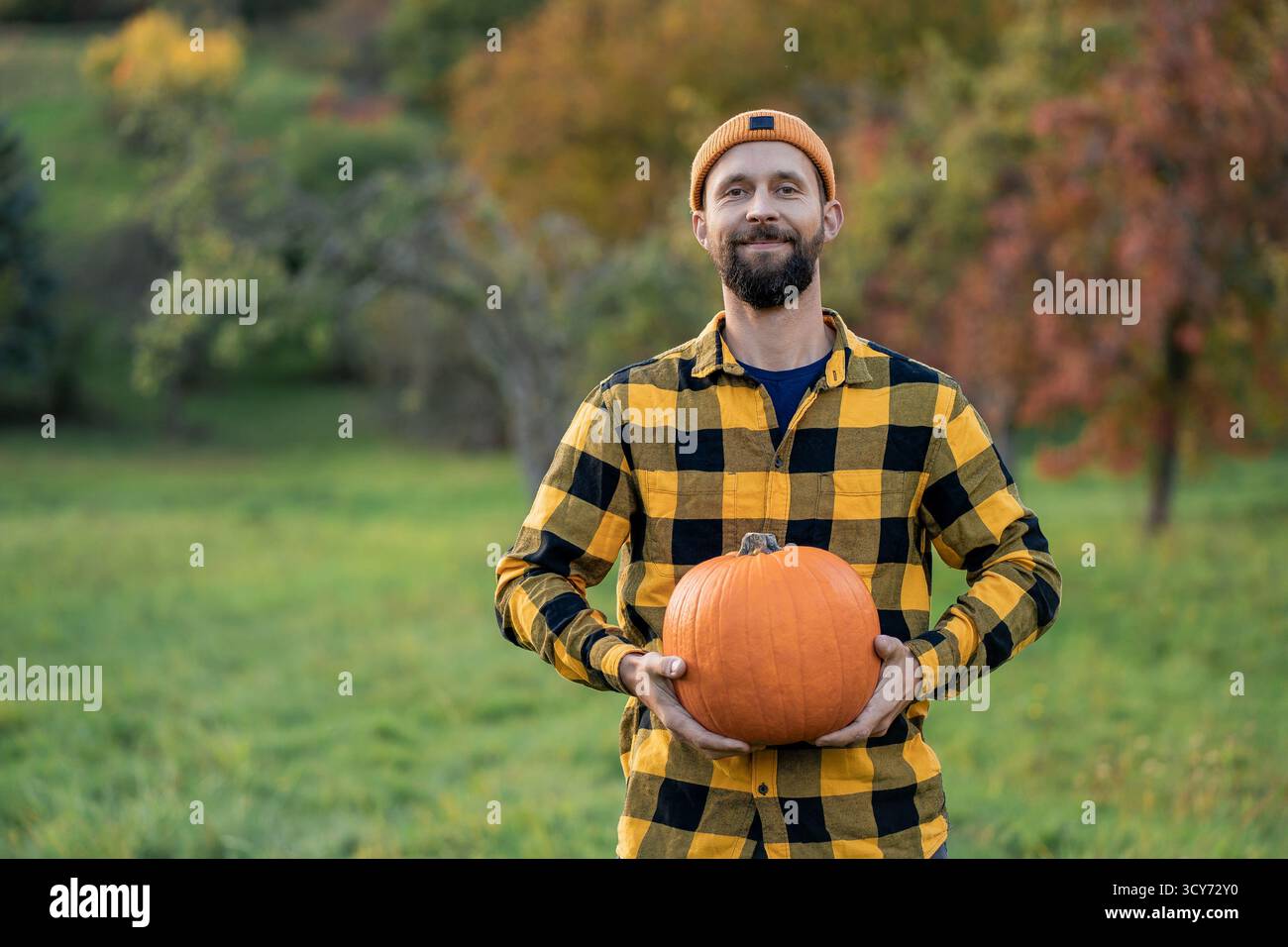 Portrait of young man with beard in an orange hat in an autumn ...