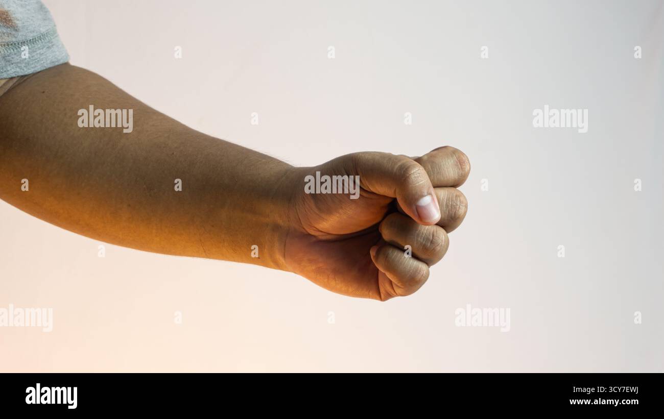 Male hand forming a tight fist on white background under warm ambient ...