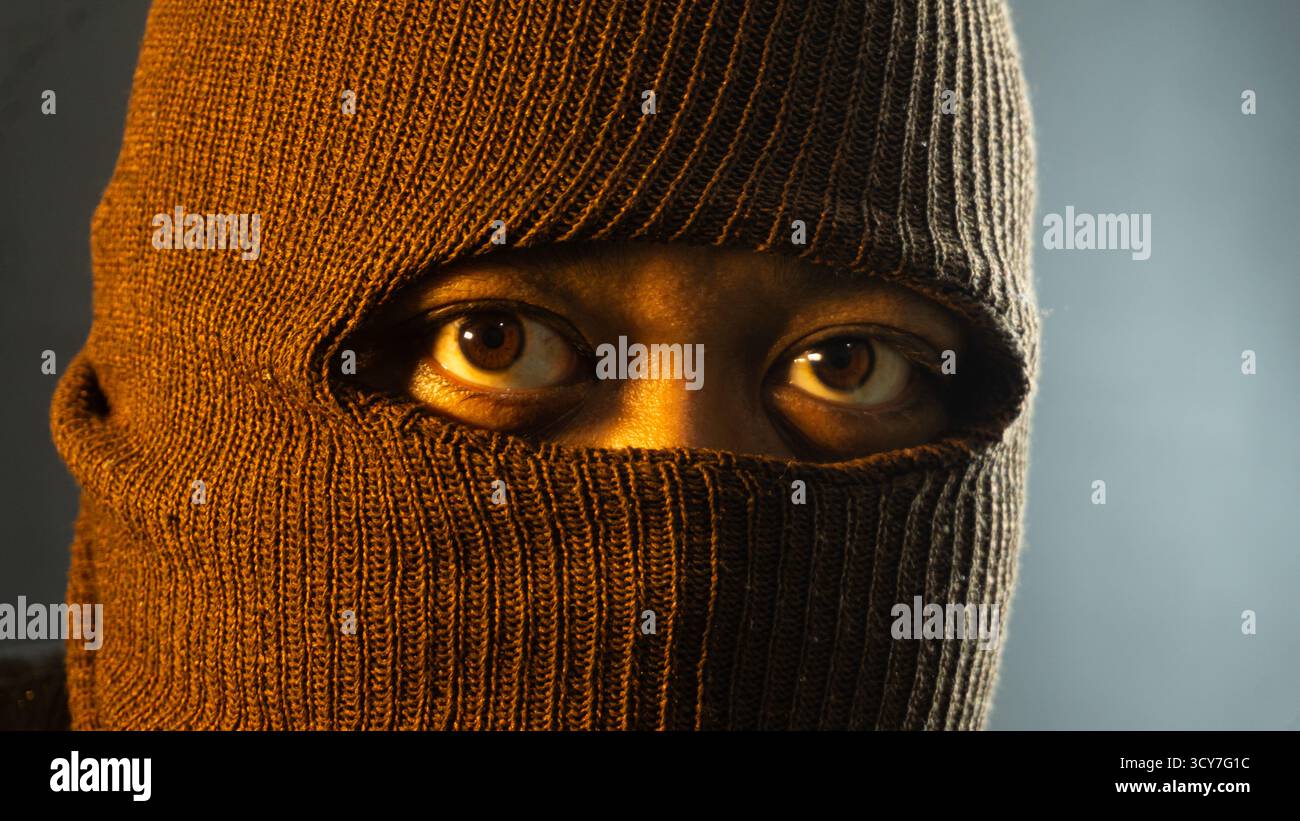 Close-up portrait of male face with brown fabric mask and warm lighting ...