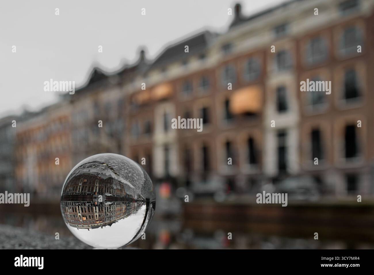 Glass ball on a canal edge shows an inverted row of canal houses and ...