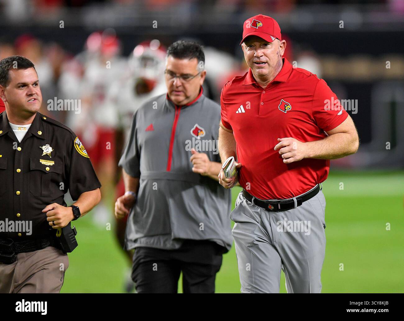 Louisville head coach Jeff Brohm, right, runs off the field after his ...