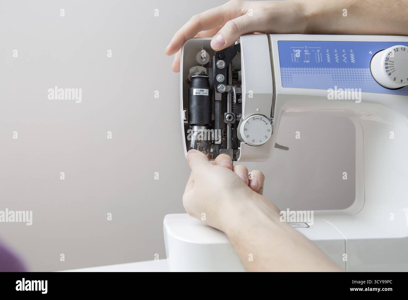 Master repairing white sewing machine standing on blank gray background ...