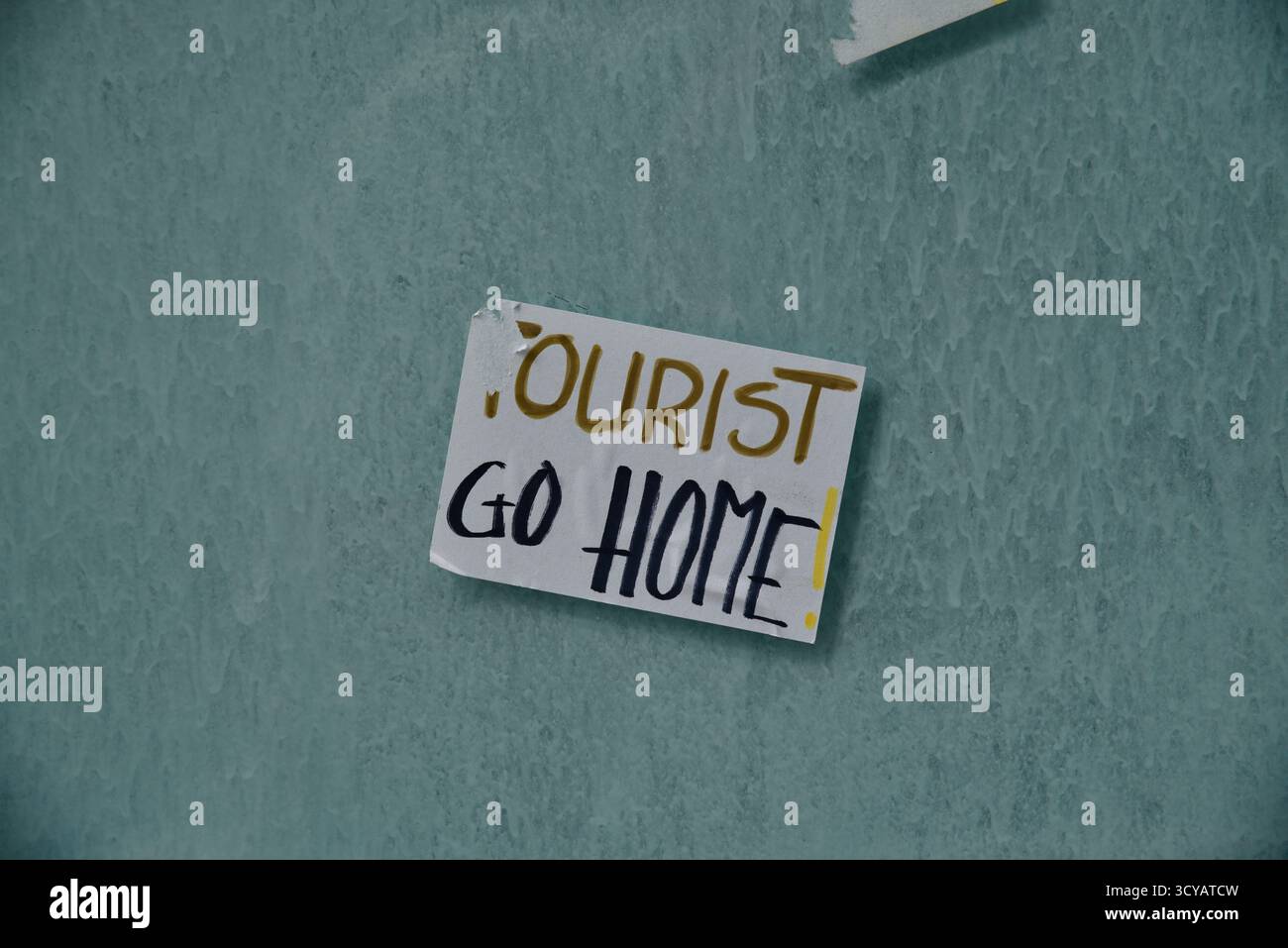 "Tourist Go Home" graffiti sign on walls of building reflecting ...