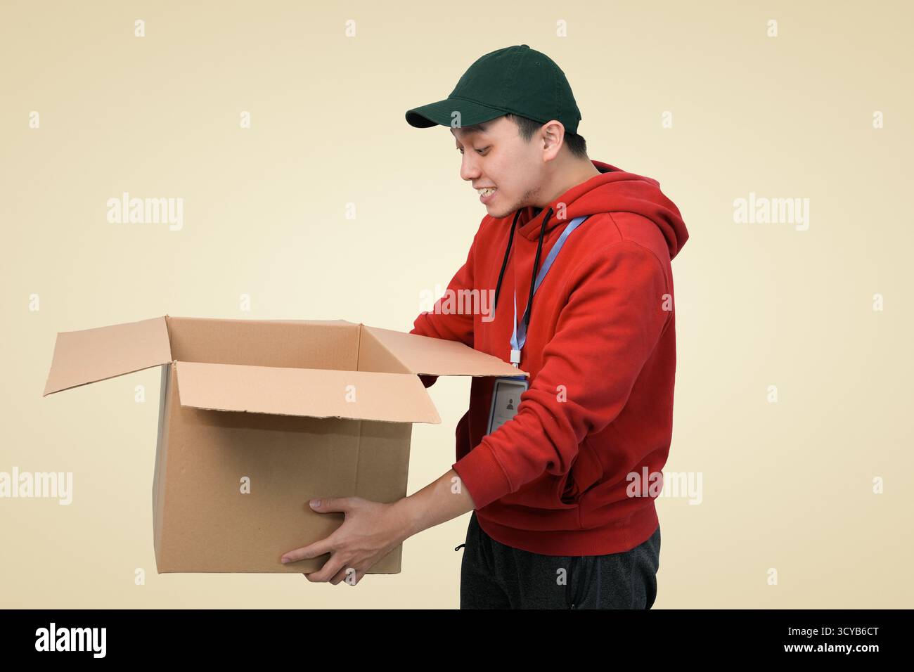 young man in red hoodie carrying open cardboard box, surprised ...