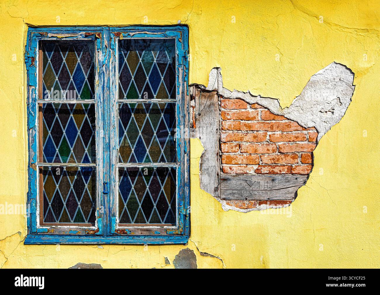 An old townhouse window with flaking paint and damaged render ...