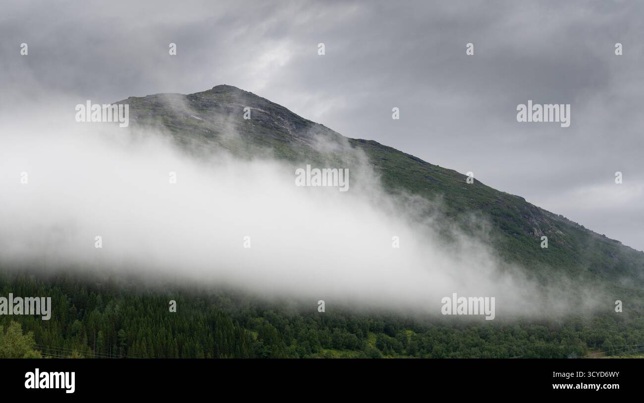 A stunning mountain landscape shows dense fog creeping up the slopes ...