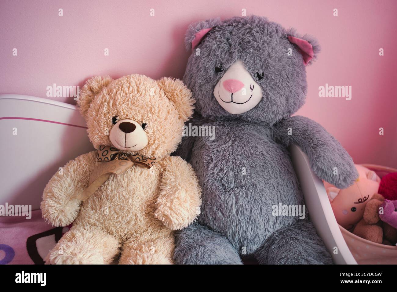 Two cute teddy bears sitting together on pink bed in cozy children room ...